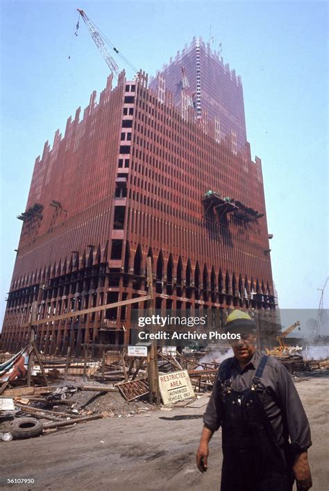A Construction Worker Walks Past The Emerging Structure Of The Twin