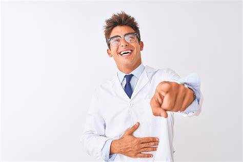 안경과 코트를 입은 젊은 잘생긴 Sciencist 남자 는 고립 된 흰색 배경 에 당신을 웃고 몸에 손으로 카메라에 손가락을 가리키는 수치스러운 표정 가리키기에 대한 스톡