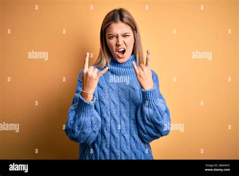 Young Beautiful Blonde Woman Wearing Turtleneck Sweater Over Yellow