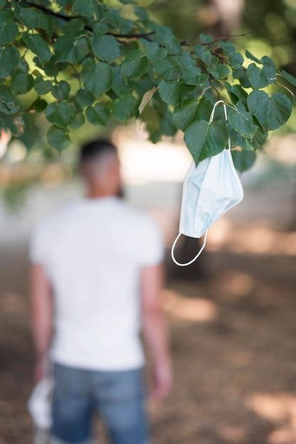 Free Photo Man Leaving His Medical Mask In A Tree