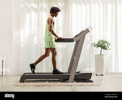 Full Length Profile Shot Of An African American Guy On A Treadmill