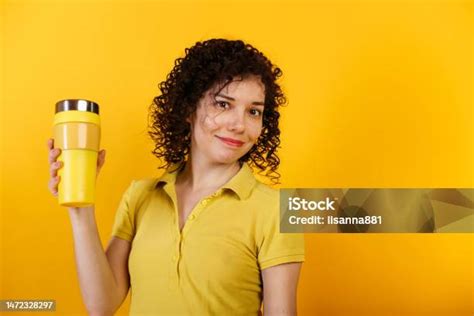 웃는 젊은 여자는 커피나 차와 함께 열 머그잔을 들고 있다 밝은 빨간 셔츠와 노란색 티셔츠를 입은 곱슬 소녀 여성 손에 제로