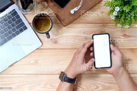 남자의 손을 나무 책상 및 사무실 용품에 모바일 스마트폰을 사용 하 여 그래픽 디스플레이 몽타주에 대 한 빈 화면 휴대 전화