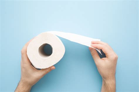 남자의 손은 밝은 파스텔 파란색 배경에 부드러운 흰색 화장지 롤을 들고 위생 개념입니다 근접 촬영 촬영 지점입니다 평면도 화장실