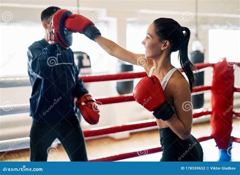 Female Boxer Kick Boxing Mitts Held By Personal Trainer At Fitness Gym