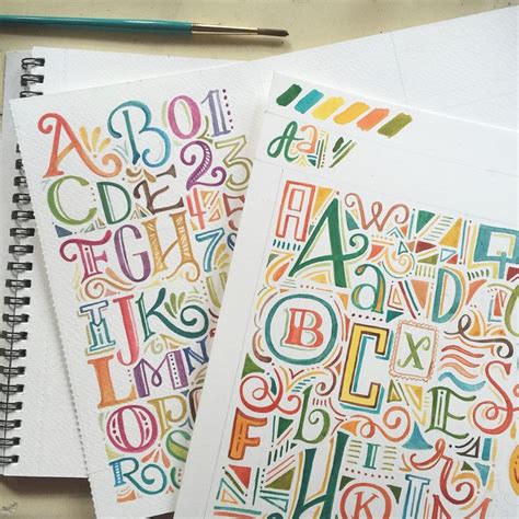 Two Notebooks With Colorful Lettering On Them Next To A Pen And Paper