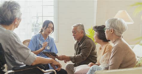 행복 쾌활한 노인 여성과 남성이 여성 간병인과 이야기하는 간호사 의사가 거실에서 건강 검진을 받고 있고 요양원의 거실에 앉아 있는 노인 부부와 간병인 사진