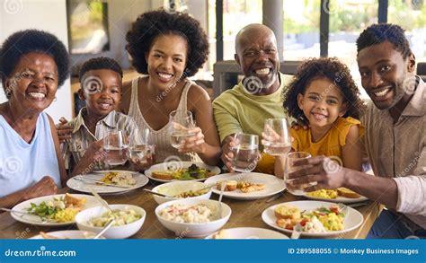 Multi-Generation Family Around Table Doing Cheers with Water before Serving Food for Meal at ...