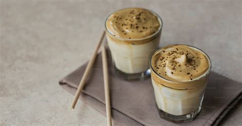 달고나 휘핑 커피 인스턴트 크림 아이스 커피 밝은 베이지색 배경에 커피 우유 얼음 조각이 있는 칵테일이 모의합니다 텍스트를 위한 복사 공간이 있는 트렌디한 음료