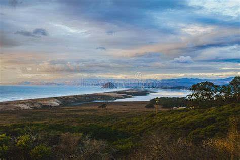 A Rocky Beach And Elfin Forest And Sunset Lit Cloudy Sky Casting A