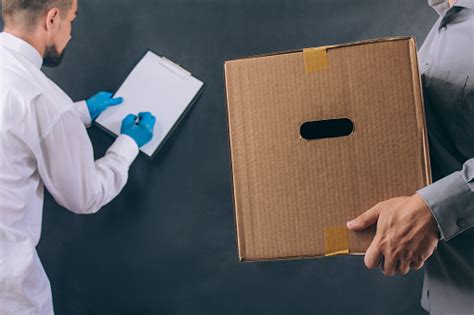 골판지 상자를 가진 남자는 클라이언트에 패키지를 제공합니다 어두운 배경에 배달 서비스 개념 2명에 대한 스톡 사진 및 기타