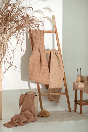 나무 벤치에 흙 색조의 천연 와플 린넨 수건과 대나무 칫솔 등나무 바구니 및 비누 디스펜서가있는 수건 사다리 데일리 바디 케어 스파 및 웰빙 제로 폐기물 욕실 개념 개념에