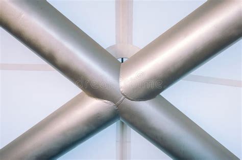 Metallic Intersecting Pipes Creating A Geometric Pattern In An Industrial Setting Stock Photo