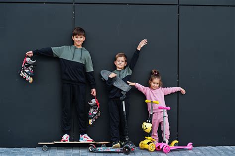 검은 현대 벽에 야외에서 세 아이 스포츠 가족은 스쿠터와 스케이트와 야외에서 자유 시간을 보낸다 12 13세에 대한 스톡 사진 및 기타 이미지 Istock