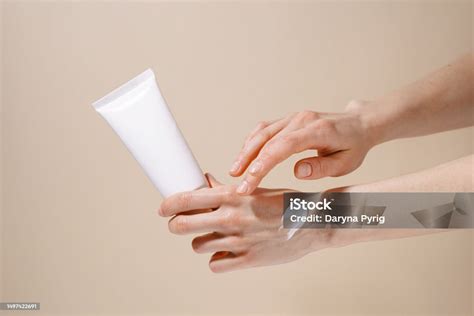 하얀 모형 항아리를 들고 베이지색 격리된 배경에 크림 샘플 견본을 바르고 있는 여성의 손 아름다움과 미학 보습 및 피부 관리의 개념 디자인을 위한 이미지 가꿔주기에 대한