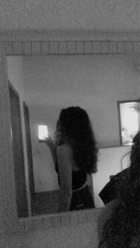 A Woman Standing In Front Of A Bathroom Mirror Looking At Her