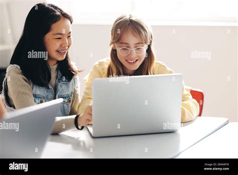 Happy Female Students Assisting Each Other As They Do A Digital