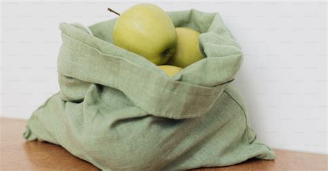 나무 테이블에 면 가방에 신선한 사과입니다 제로 웨이스트 쇼핑 재사용 가능한 녹색 가방에 담긴 유기농 과일 친환경 플라스틱 무료 식료품 지속 가능한 라이프 스타일