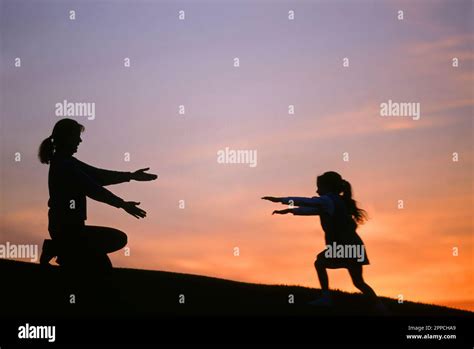 Silhouette Of A Young Mother And Daughter Running Towards Each Other At