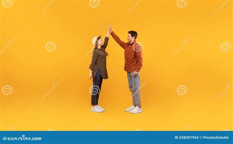 Happy Couple Giving High Five Celebrating Success Over Yellow