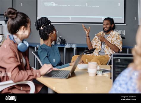 Joyful Indian Programmer In Wheelchair Demonstrating Code On Digital Board To His Female