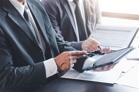 금융 및 투자 개념 사업가는 파트너와 함께 비즈니스 금융 투자 계획을 발표하고 투자자 동료는 노트북과 디지털 태블릿이 있는 사무실 테이블에 재무 그래프 데이터로 새로운 투자