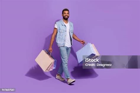 멋진 예쁜 남자의 전체 길이 사진 청바지 허리 코트를 입고 쇼핑객 빈 공간 고립 된 보라색 배경을 들고 걷는 쇼핑에 대한 스톡 사진 및 기타 이미지 Istock