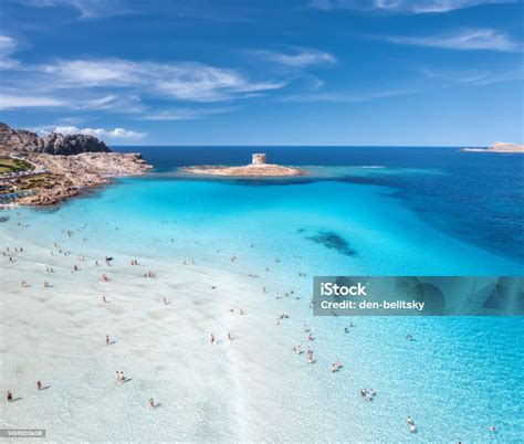 화창한 여름날 유명한 라 펠로사 해변의 공중 전망 스틴티노 사르데냐 섬 이탈리아 모래 해변 수영하는 사람들 맑고 푸른 바다 오래된 탑과 구름이 있는 하늘의 최고 전망 열대