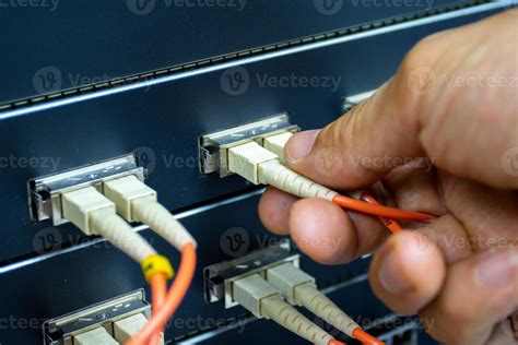 Hand Of A Man Holding The Network Fiber Optic Cables To Connect The Port Of A Switch To Connect