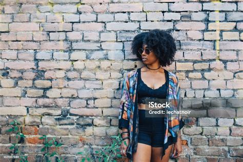 벽돌 벽에 서 있는 아름 다운 젊은 아프리카계 미국인 여자의 초상화 Feministiskt Initiativ에 대한 스톡 사진