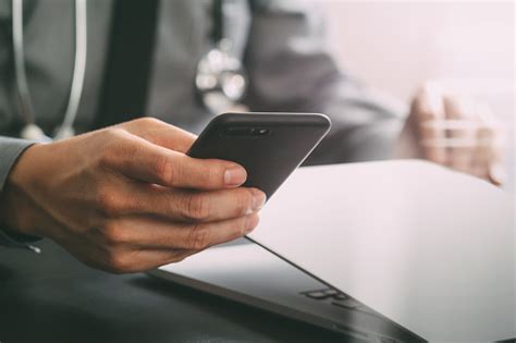 어두운 나무 책상에 휴대 전화 및 노트북 컴퓨터와 청진 기를 사용 하는 스마트 의료 의사의 클로즈업 간호사에 대한 스톡 사진 및
