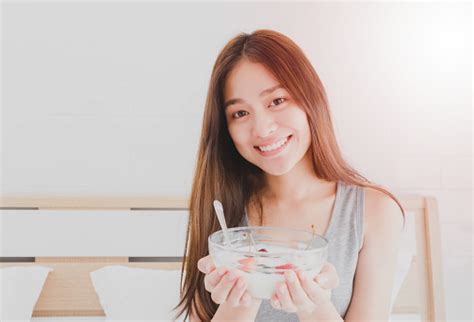 아침에 한 그릇을 들고 아시아 아름 다운 웃는 여자 빈티지 톤 침실 아침 배경에서 과일 요구르트입니다 건강과 미용 개념입니다