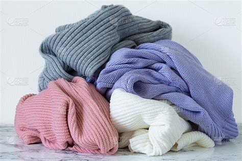 大理石桌上一堆暖和的毛衣秋冬衣服捐赠