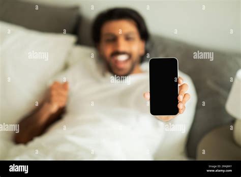 Happy Millennial Middle Eastern Guy Woke Up Show Smartphone With Blank