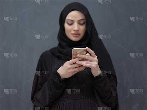 年轻的穆斯林女商人穿着传统服装或阿拉伯长袍使用智能手机