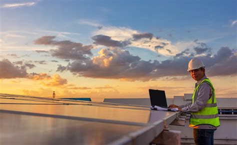 일몰 하늘의 옥상에 있는 태양전지 패널에서 노트북을 사용하는 엔지니어 태양광 농장에서 일하는 엔지니어 전력을 위한 에코 기술 건설 현장에 대한 스톡 사진 및 기타 이미지