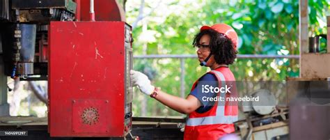 안전 고글을 착용한 여성 작업자가 선반 기계를 제어하여 부품을 드릴링합니다 금속 선반 산업 제조 공장 25 29세에 대한 스톡