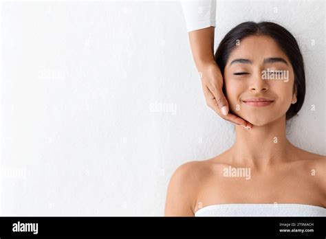 Joyful Young Indian Woman Relaxing During Face Lifting Massage Stock