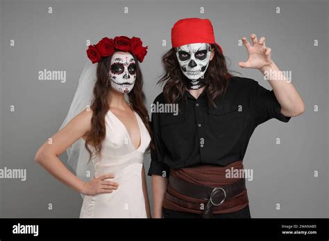 Couple In Scary Bride And Pirate Costumes On Light Grey Background