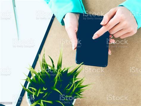 현대 사무실 인테리어에서 컴퓨터에서 작업 하는 동안 스마트 폰을 사용 하 여 여성의 손의 클로즈업 사업가 로프트 인테리어에 그녀의 핸드폰에 문자 메시지를 입력 금융에 대한