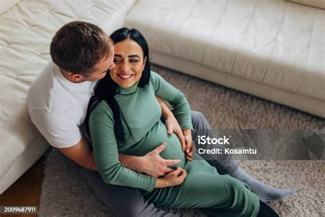 한 남자가 거실 카펫에 앉아 미소 짓는 임신한 아내에게 키스하고 껴안는다 임신에 대한 스톡 사진 및 기타 이미지 임신 커플 행복 Istock