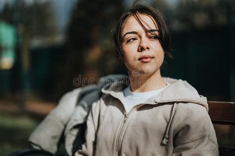 Relaxed Young Woman Basking In Sunlight On A Peaceful Park Bench Stock