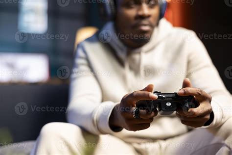 Bipoc Man Playing Shooter Videogame In Neon Lit Apartment Holding Controller Close Up Shot