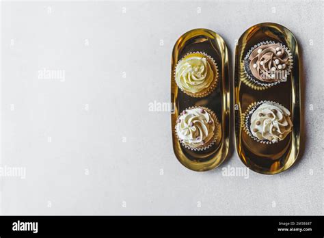 Top Down View Of Four Frosted Cupcakes With Sprinkles On Small Golden