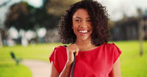 Black Female At Pretty Park Smiles Cheerfully At Camera Waves And