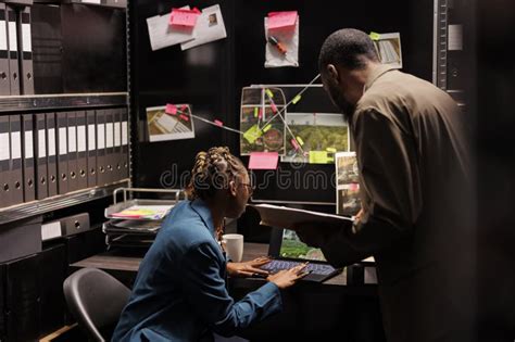 Detectives Analyzing Case File And Searching Information On Laptop