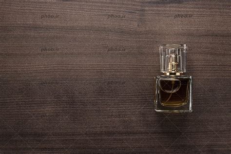 عکس یک شیشه ادکلن در پس زمینه چوبی عکس با کیفیت و تصاویر استوک حرفه ای
