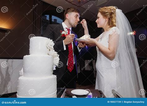 Bride And Groom Tasting Together Their Stylish Wedding Cake Piece With