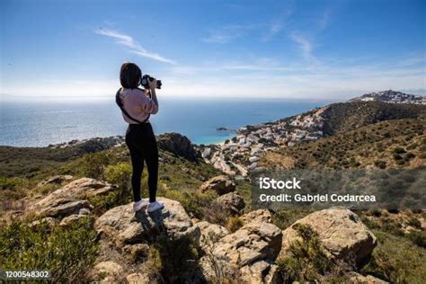 절벽에 서있는 아름다운 여성 사진 작가가 복사 공간으로 스페인의 배경에 지중해와 전문 카메라로 사진을 찍고 관광에 대한 스톡 사진 및 기타 이미지 Istock