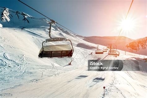 밝은 화창한 저녁에 힐랜드 알프스 산 겨울 리조트의 스키 리프트 빈 로프웨이 스키 체어리프트 케이블 로는 스키와 스노우보드를 즐기실 수 있습니다 배경에 빛나는 일몰 하늘